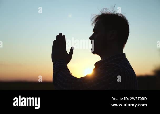 Christian man praying at sunset close-up. Men in front of the sky in ...