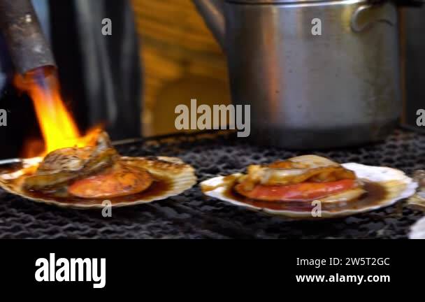 Slow motion of vendor cooking scallops on steel grill in asian fish ...