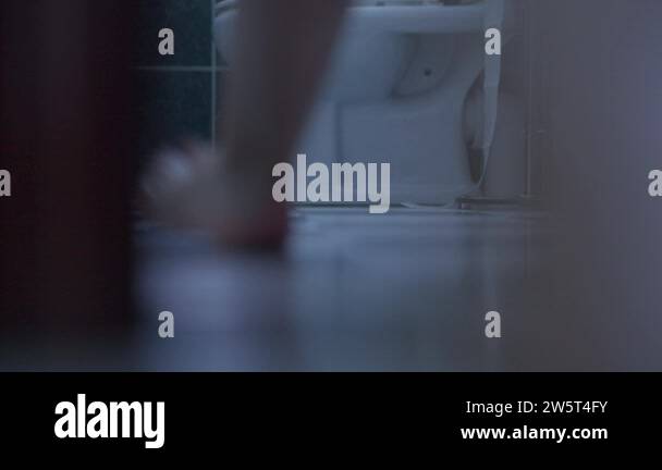 Barefoot Caucasian male legs entering toilet room sitting down taking ...