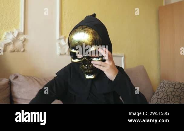 The child at home wears a scary skull mask with a black hood. The boy ...