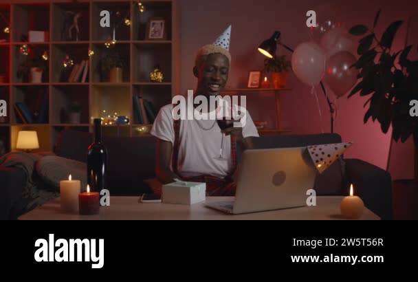 Young cheerful guy cheering to laptop screen with wine glass and ...