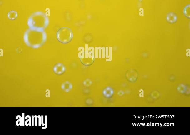 Beautiful colored soap bubbles fly indoors on a yellow background ...