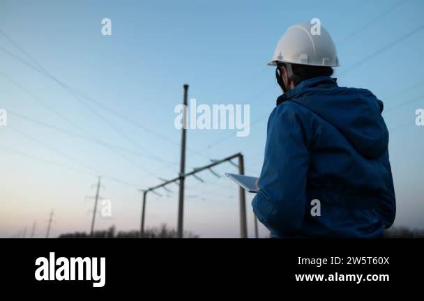 Woman power engineer in white helmet checks power line using computer ...