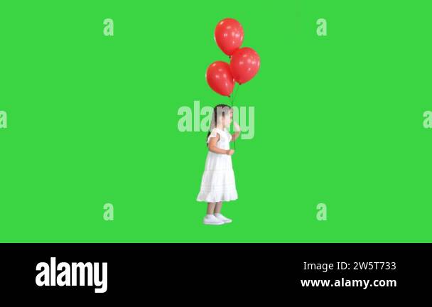 Adorable little girl holds tightly to a large bunch of helium balloons ...