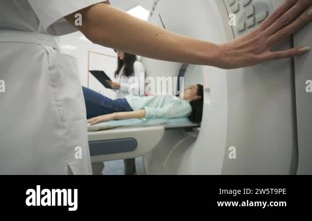 "Female patient is undergoing CT or MRI scan under supervision of two ...