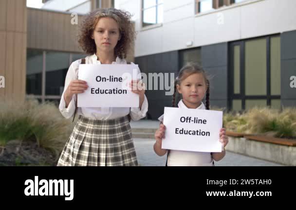 Two schoolgirls with placards are standing in front of the school ...