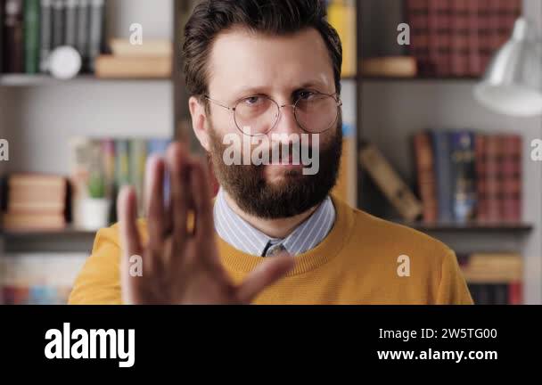 Man show STOP, NO. Serious displeased bearded man in glasses in office ...