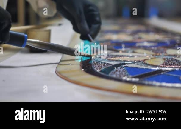 Close-up Soldering stained glass seams. Gloved hands with a soldering ...