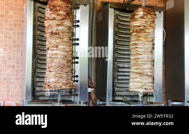 Cooking traditional fast food doner kebab meat on a rotary grill ...