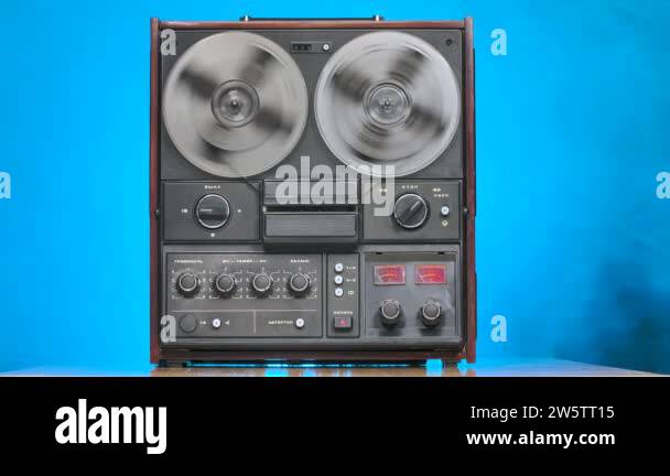 Reel to reel tape recorder playing against a smoky studio background ...