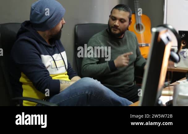 Friends sitting on music studio listening their song and following the ...