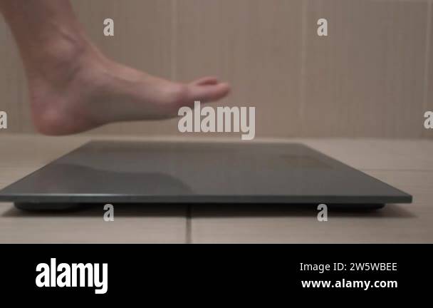 Unrecognizable barefoot woman steps on bathroom scales and measure ...