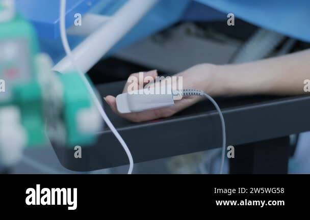 Girl's hand with a pulse oximeter in the operating room. Modern medical ...
