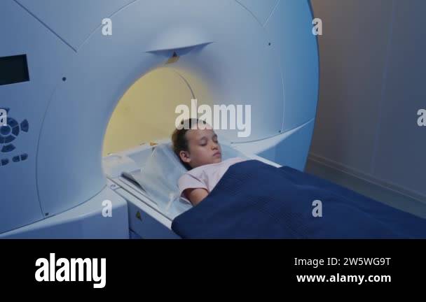 Slowmo shot of little girl on scanner table getting inside MRI machine ...