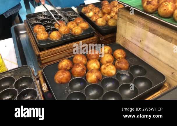 Chef hand pick up Japanese snack food takoyaki from takoyaki pan into ...