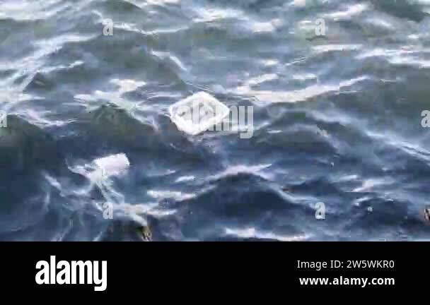 Disposable plastic utensils float on sea waves. Plastic pollution of ...
