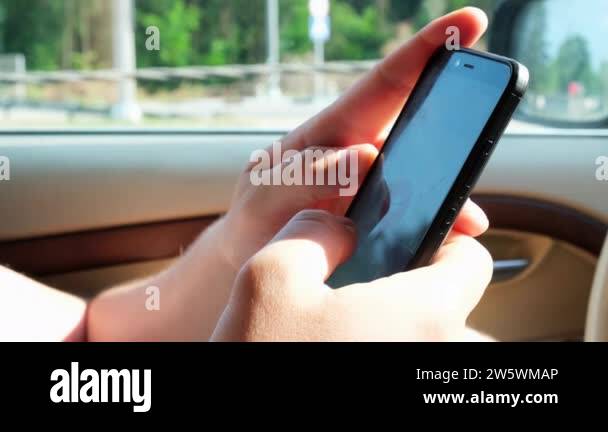 Mans hand is holding phone and touch the screen with fingers in a car ...