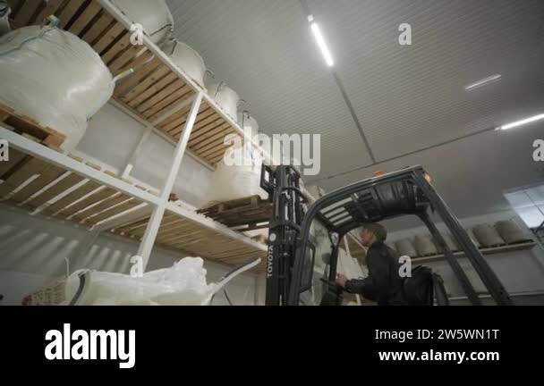 Warehousing. Forklift driver stacking big bag of raw material in ...