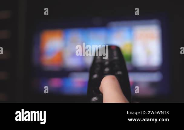 Woman hand selects internet tv channels with remote control, close-up ...