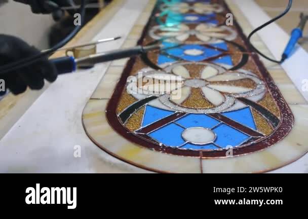 Soldering stained glass seams. Gloved artists hands with a soldering ...