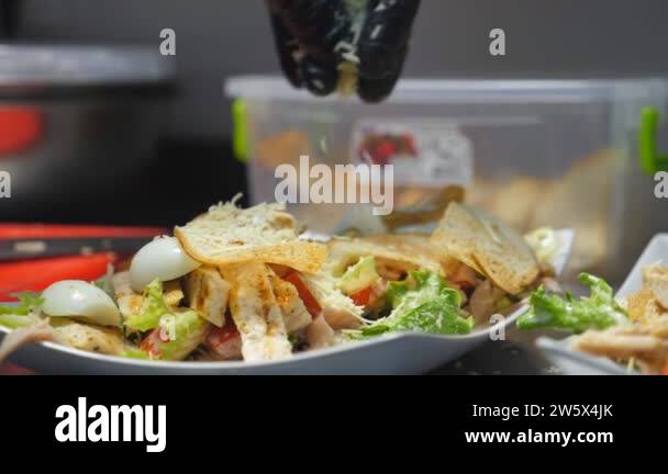 Male arm of chef throwing grated parmesan on caesar salad in white ...