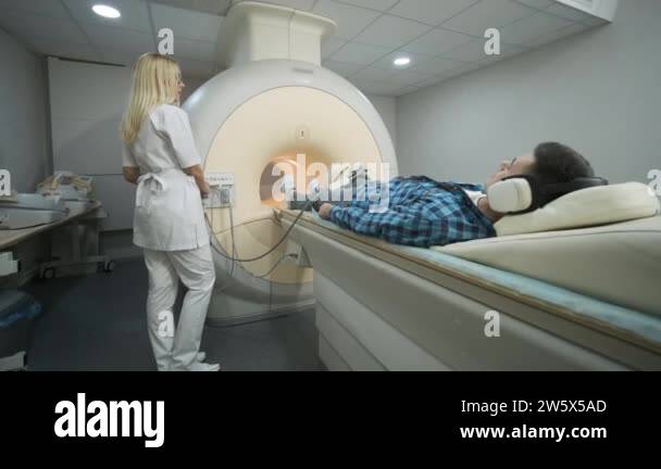 Woman doctor makes knee-joint MRI scanning. Young man patient on ...