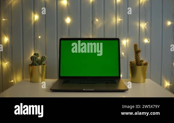 Green screen laptop computer on a homework desk in dark room with ...