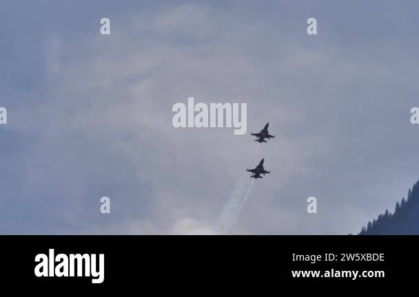 Close formation of two military fighter jet does a roll in a blue sky ...