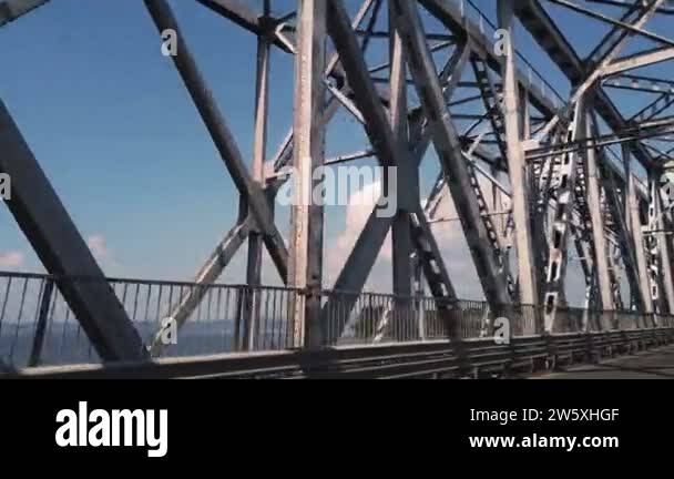 metal bridge. rough iron constructions against blue sky and river ...