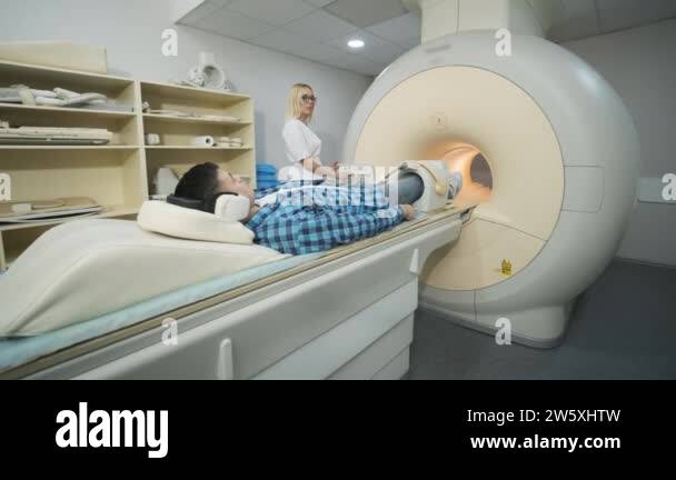 Woman doctor makes knee-joint MRI scanning. Young man patient on ...