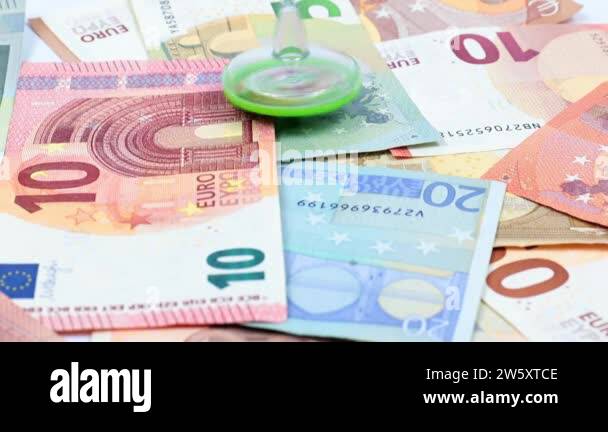 the rotation of a plastic whirligig on a pile of euro banknotes as a ...