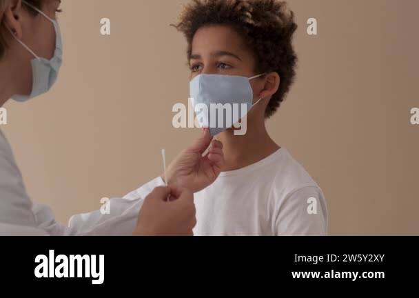 Female practitioner doctor takes nose swab of 10s patient. Little mixed ...