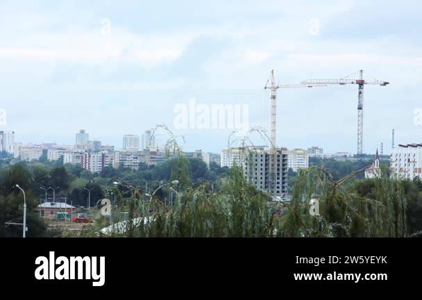 footage of cityscape, city skyline, construction cranes is building a multi-story residential ...