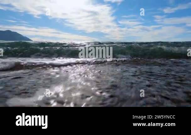 Camera lies on seashore, wave rolls over it and completely loads it ...