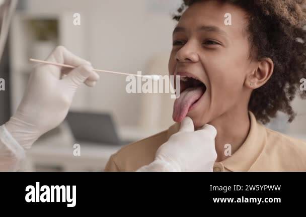 Close-up of teenage African boy opening his mouth for unrecognizable ...