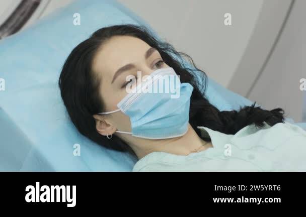 Female patient in mask is undergoing CT or MRI scan in modern medical ...