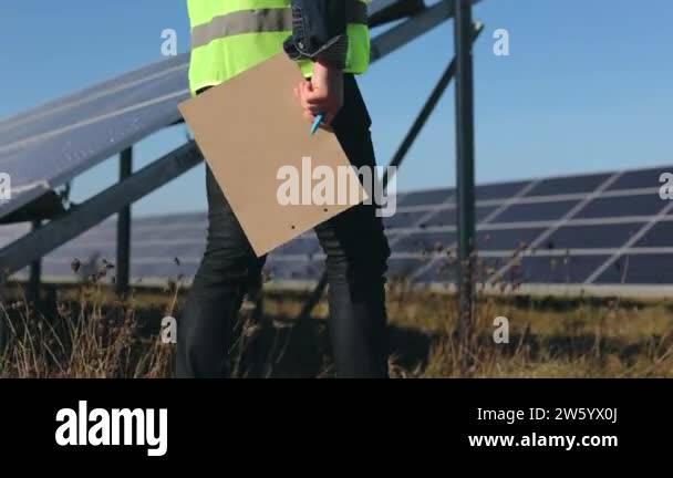 The engineer is walking through an object with solar panels. He is ...