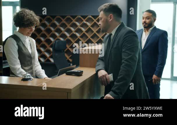 Hotel manager greeting guests taking smart phone payments standing at ...