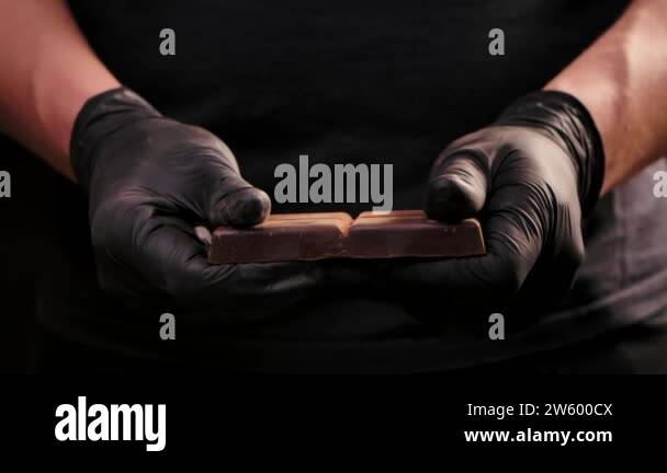 Man hands in black gloves breaking chocolate. Dark chocolate bar ...