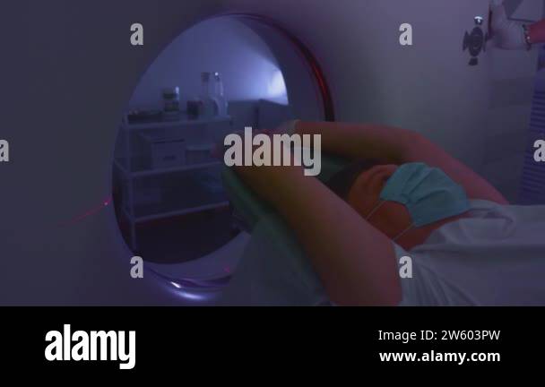 A patient in a protective medical mask lies in a modern computed ...