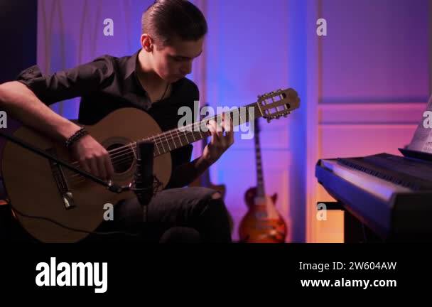 Young man plays guitar at home. Caucasian teen boy play a musical ...