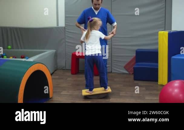 Kid girl with therapist do exercise on balance during sensory ...