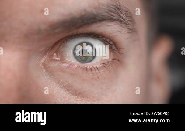 Extreme close up of surprised male opens his eye wide and stares at the ...