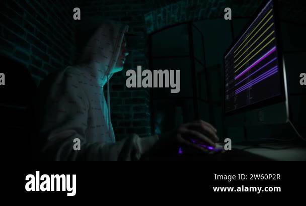 Hacker in the hood working with computer typing text in dark room. Image with effect. newest ...
