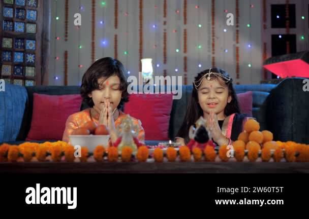Young Indian brother and his cute sister doing Puja on the auspicious festival. A table ...