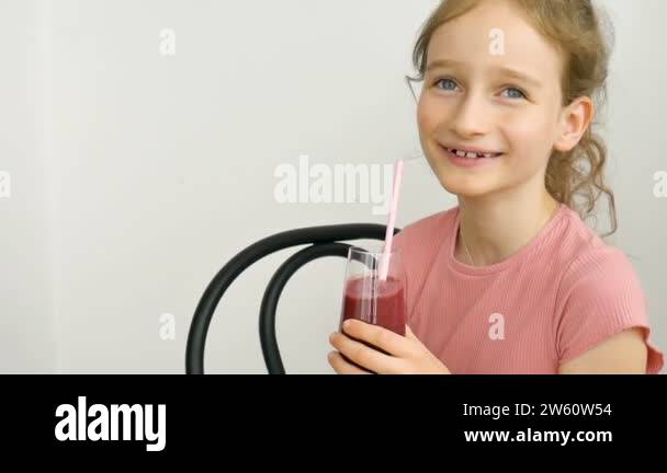 Sweet little girl drinks raspberry smoothie and smiles. Vegetarian ...