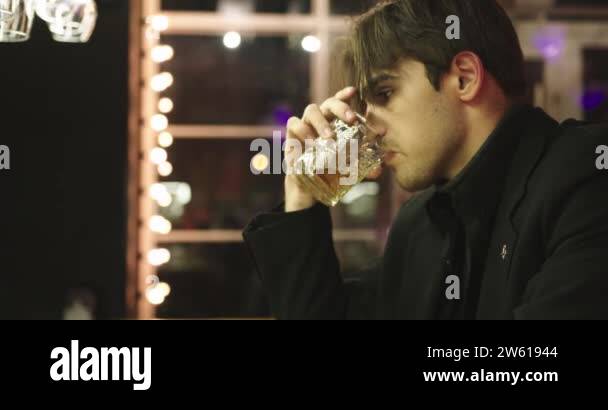 Lonely and depressed man in black clothing drinks whiskey behind the ...