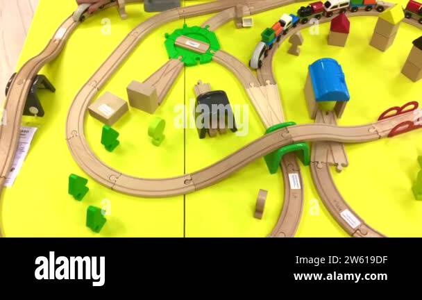 A child plays with a wooden train and builds a toy railroad at home, in ...