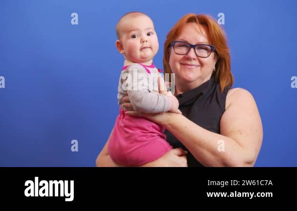 Senior woman holding her baby granddaughter kiss at home young and old people together. Baby ...