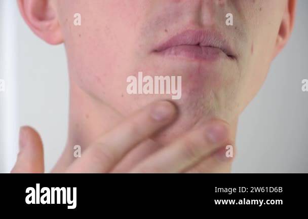 A young man strokes the skin of his face after shaving close-up in the ...